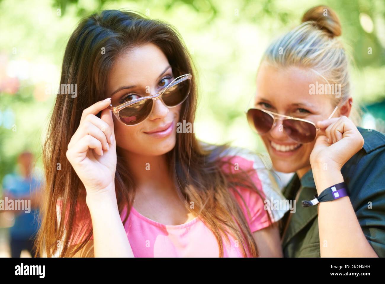 Fun and fashionable. Two young women glancing over the rim of their ...