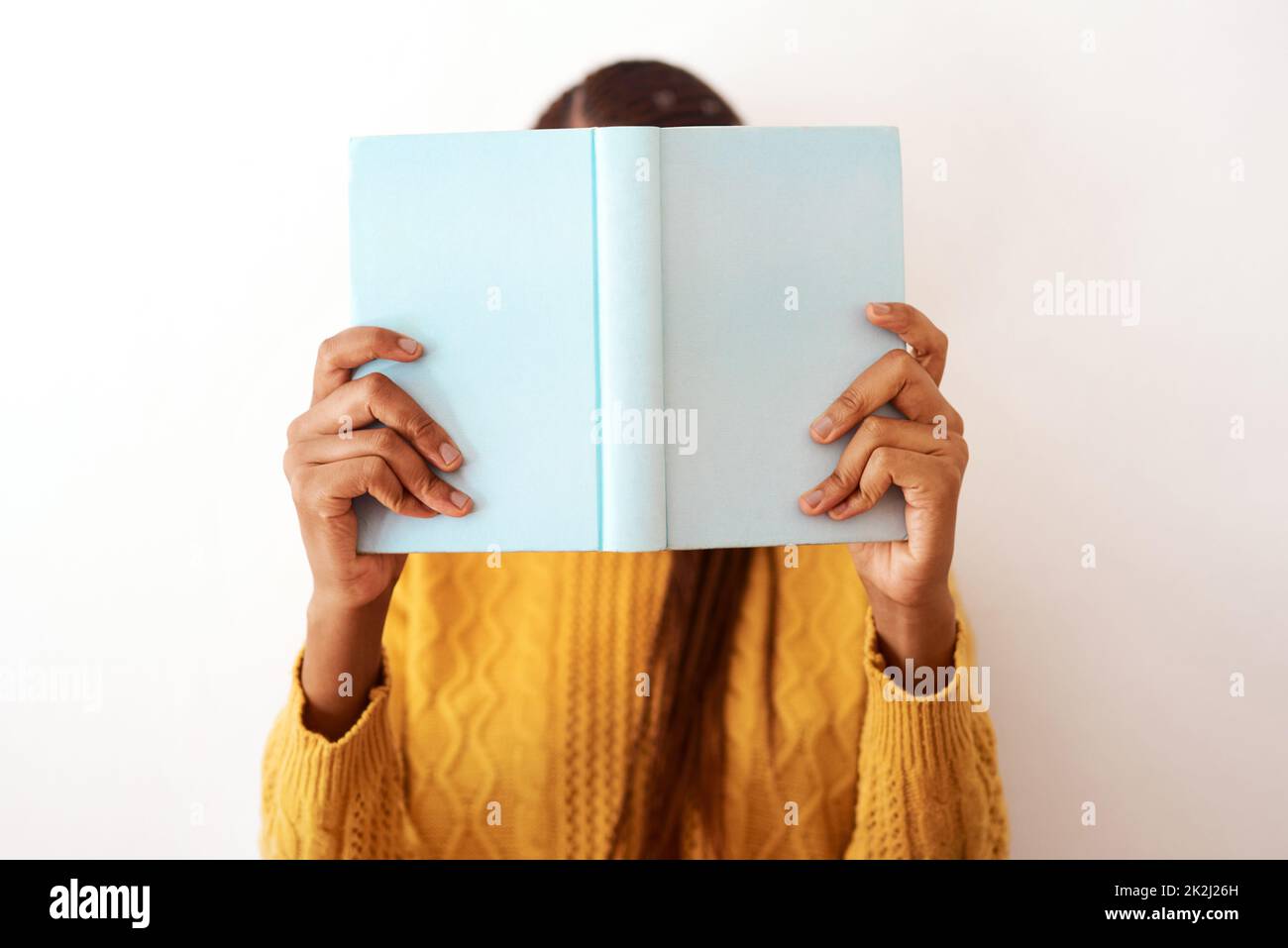 Youll find me behind the books. Studio shot of an unrecognizable woman ...