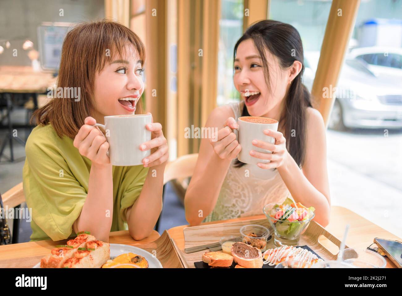 Happy young women drinking coffee in cafe shop Stock Photo - Alamy