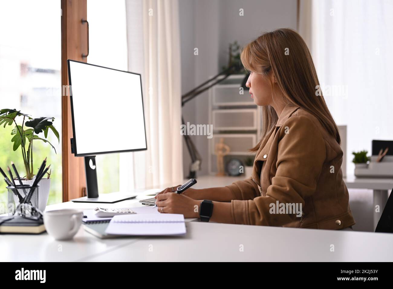 Side view of focused female entrepreneur working online with computer ...