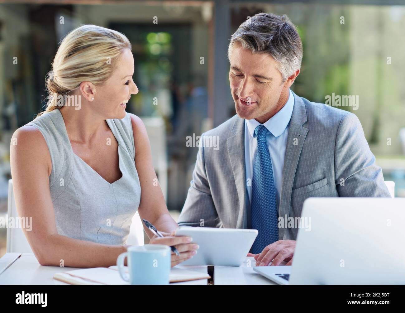 Using every device at their disposal. two mature businesspeople talking ...