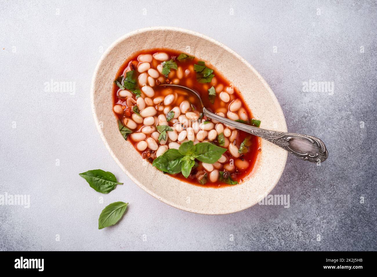 Top view of spicy dish with beans in tomato sauce with fresh basil on ...