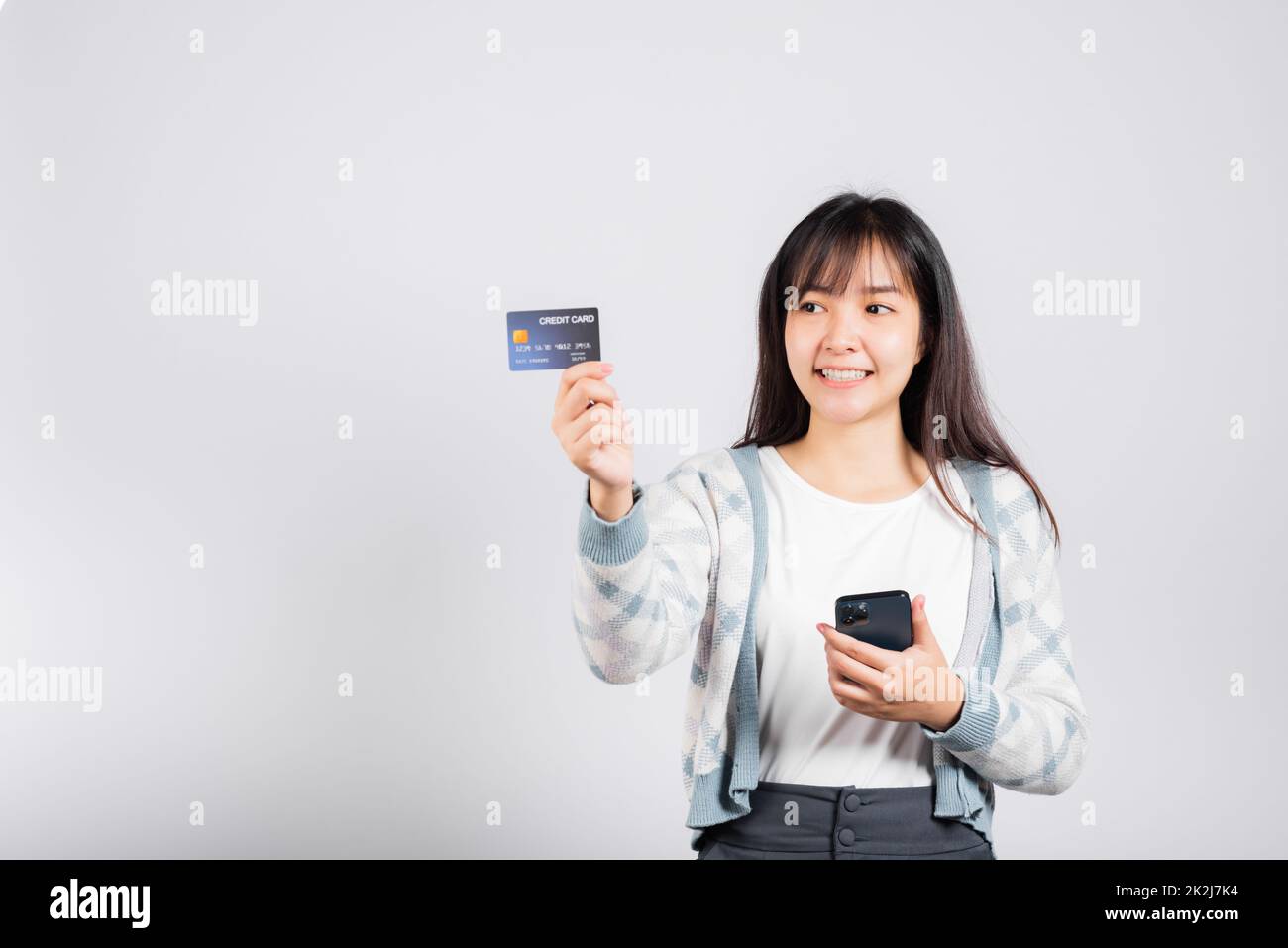 Woman excited smiling hold mobile phone and plastic debit credit bank card for payment Stock ...