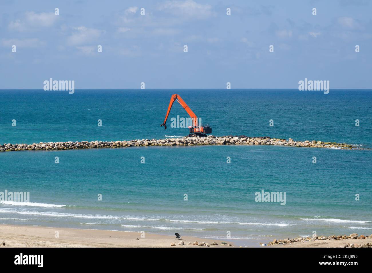 The excavator moves stones into the sea. Construction of breakwaters to ...