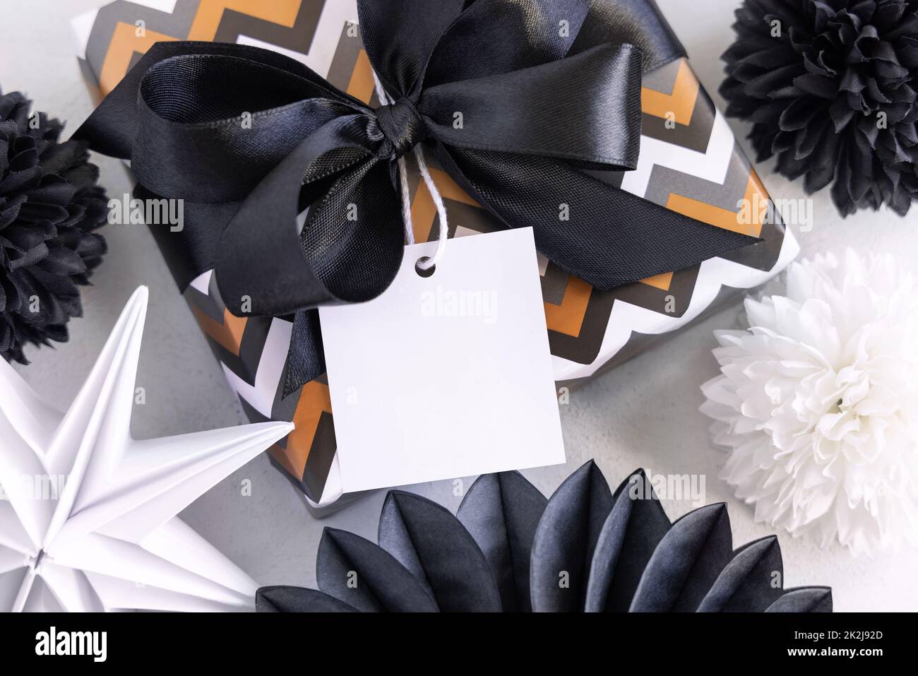 Wrapped present with blank square gift tag and black bow close up ...
