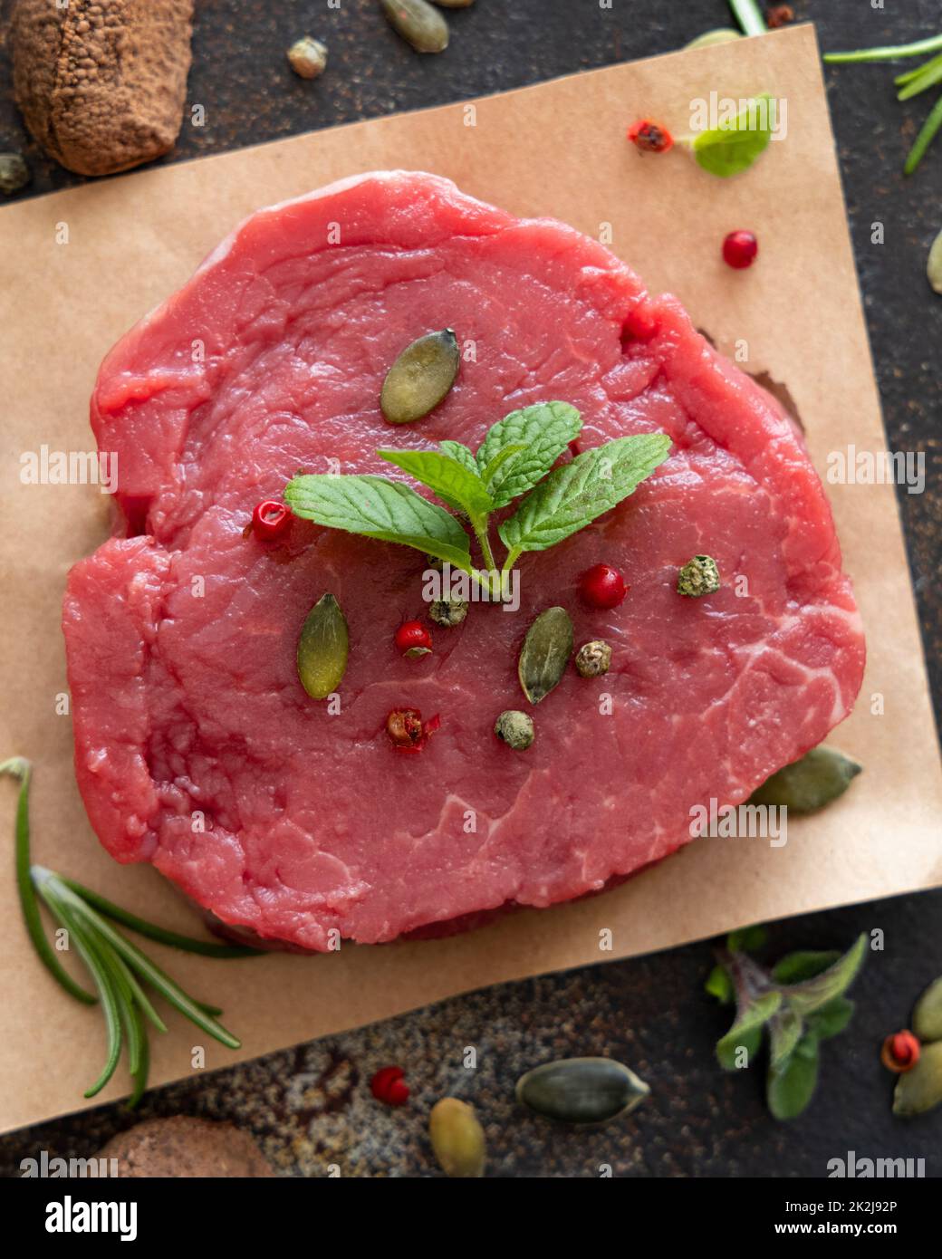 Raw beef fillet steak with herbs and spices on dark table top view ...