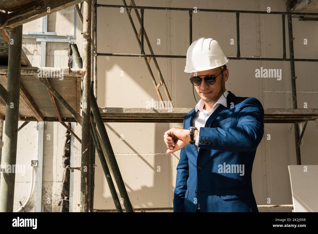 Man architect wearing formal suit and hard hat looking on his ...