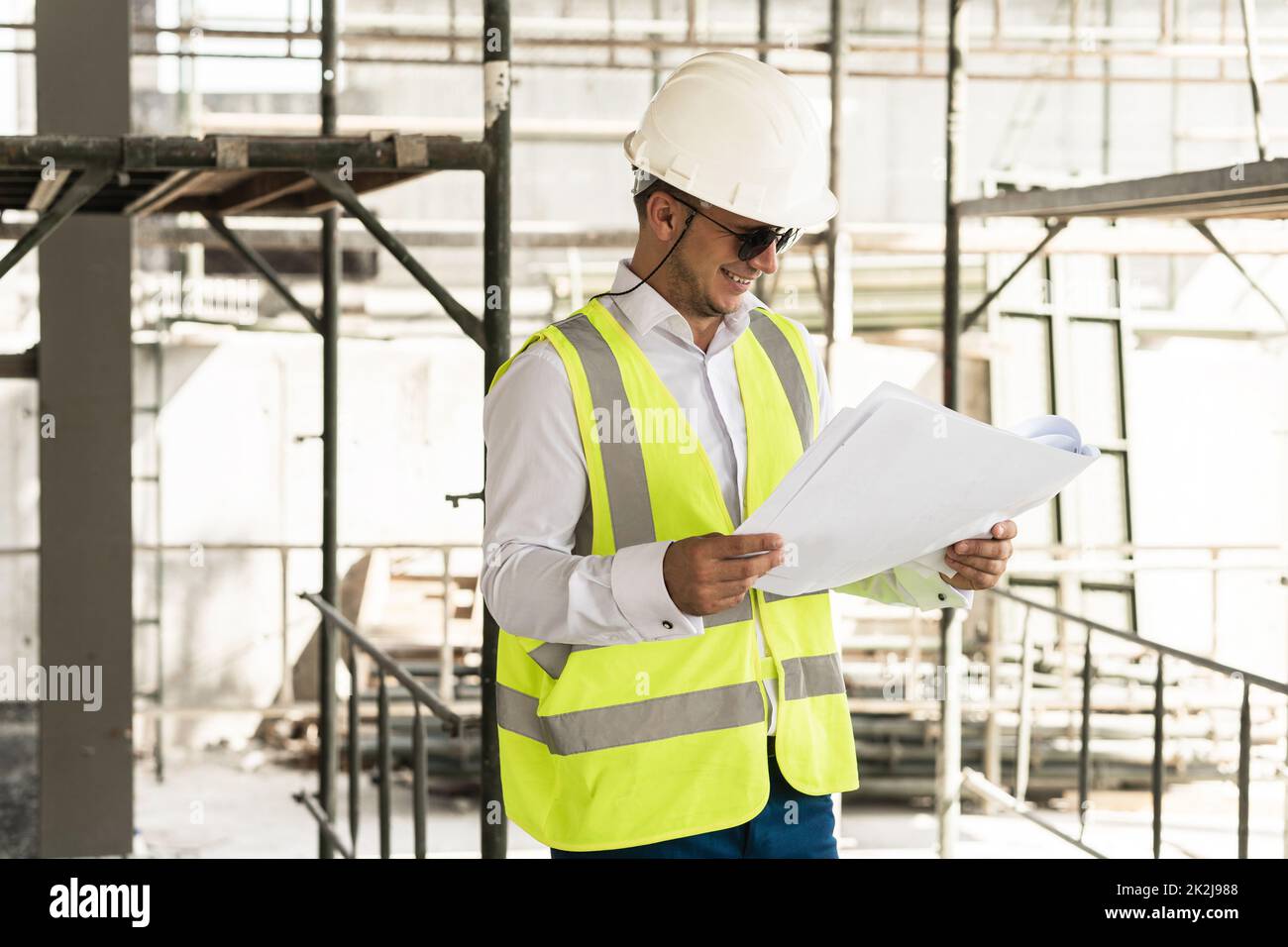 Man architect wearing safety vest with a blueprints on a construction ...
