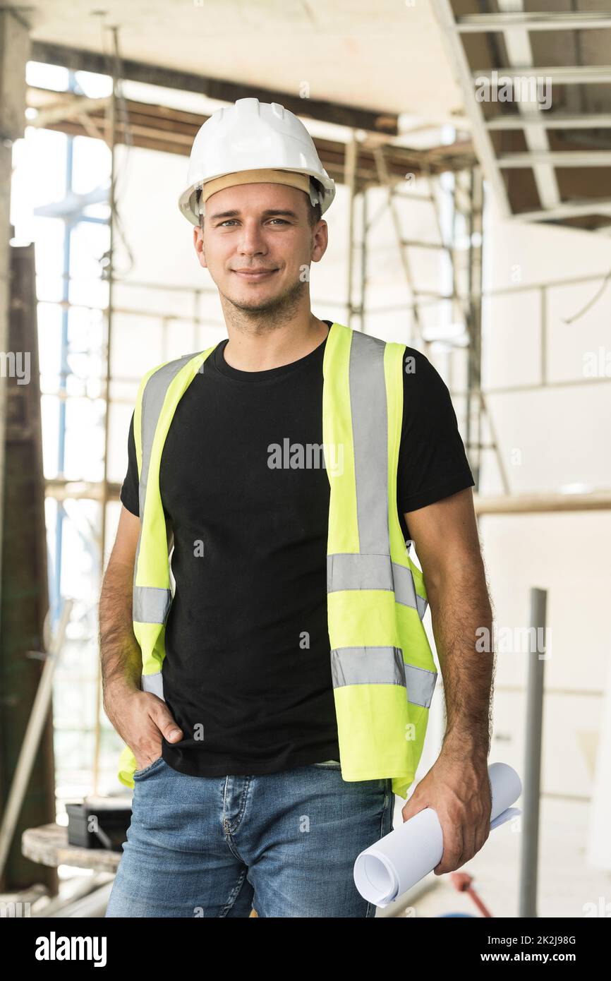 Worker wearing hard hat nad safety vest on a construction site Stock Photo - Alamy