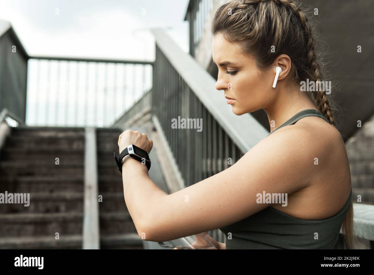 Athletic woman using smartwatch during her fitness workout on city ...