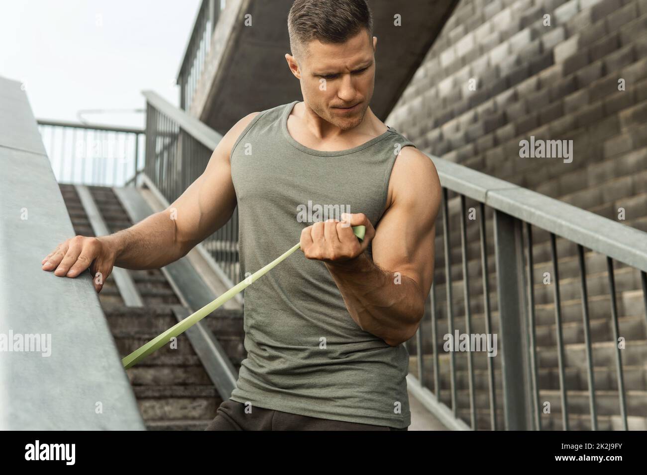 Muscular man during workout with a resistance rubber band on a street ...