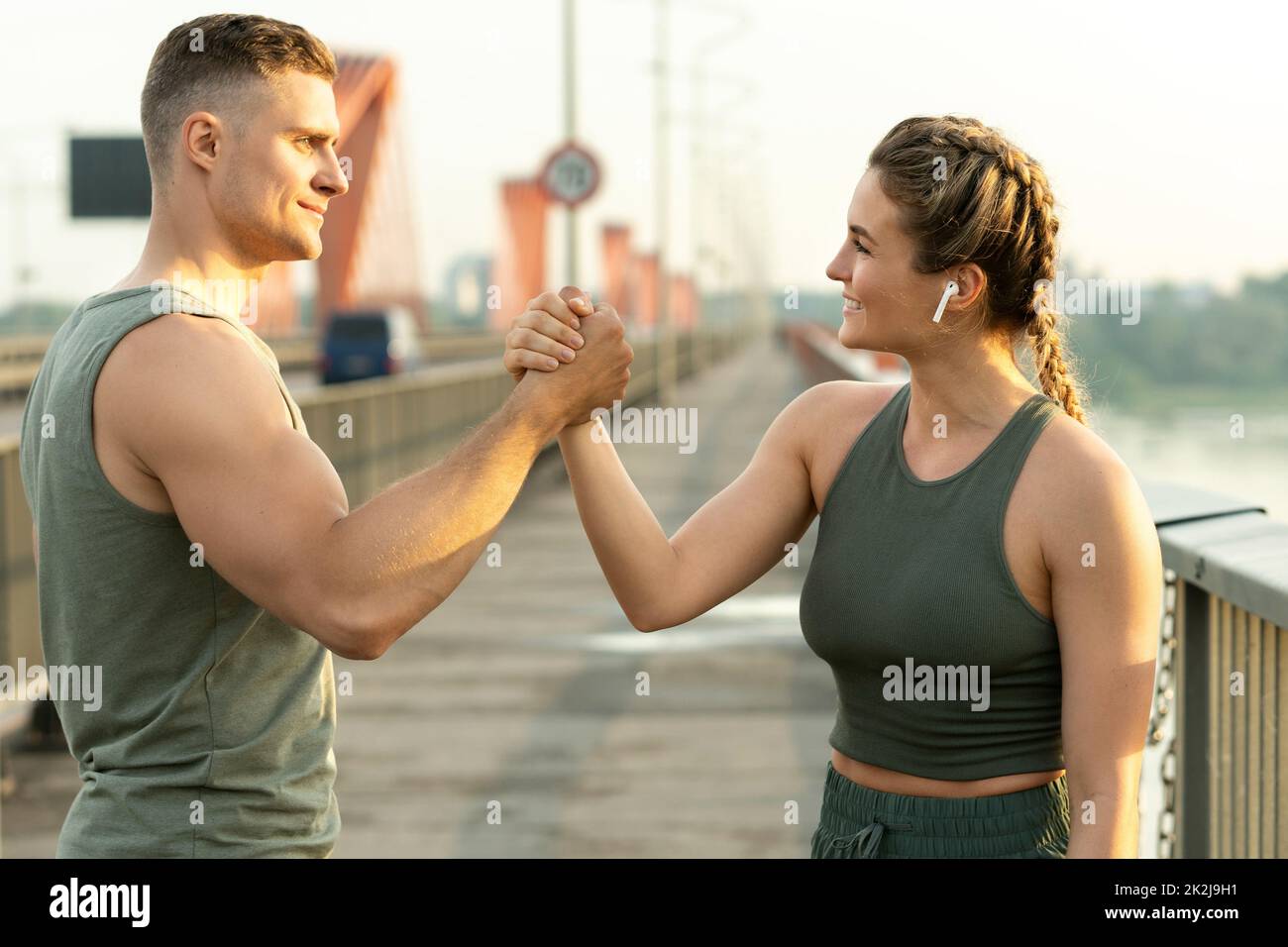 Athletic couple making handshake during fitness workout on city street ...