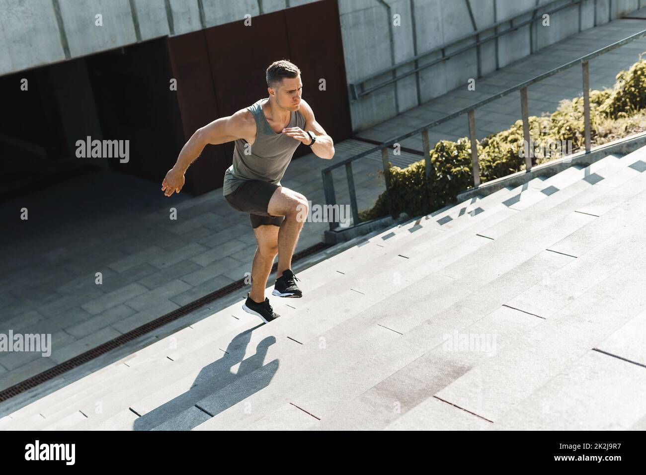 Athletic man is running upstairs by concrete staircase outdoors Stock ...
