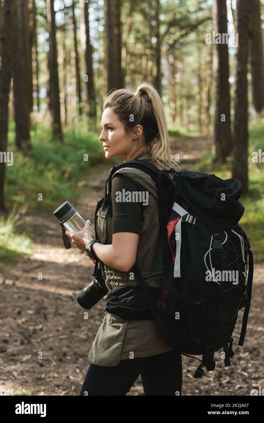 Female hiker with big backpack and reusable bottle for water in green ...