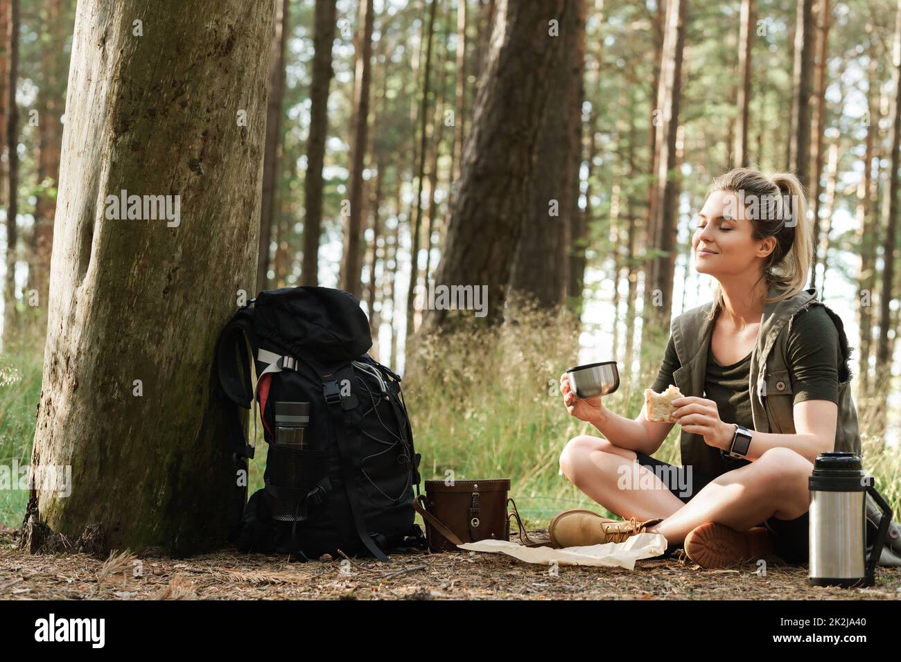 Female hiker during small halt eating sandwich in green forest Stock ...