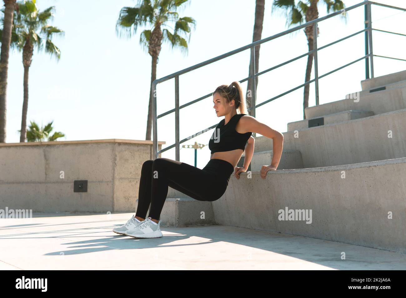 Athletic woman is doing triceps dip during summer calisthenic workout ...