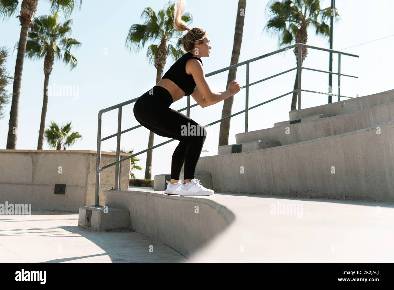Athletic woman is running on concrete stairs during her street summer ...