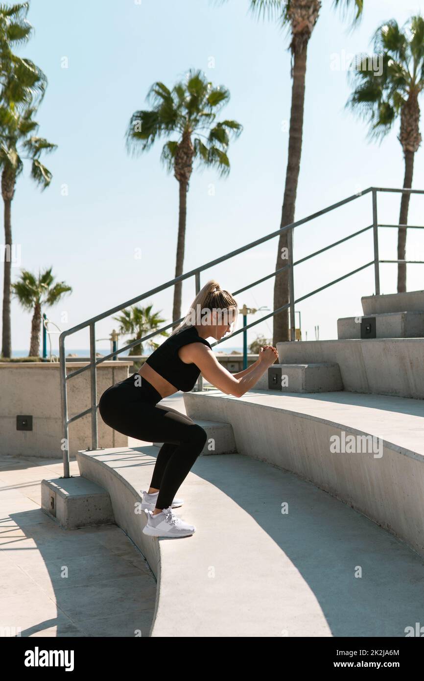 Athletic woman is running on concrete stairs during her street summer ...