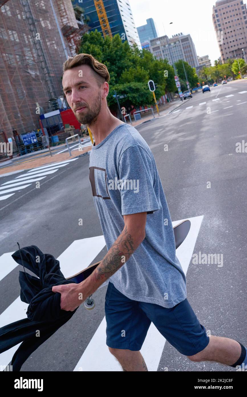 Living on the edge. Shot of a young man skateboarding through the city ...