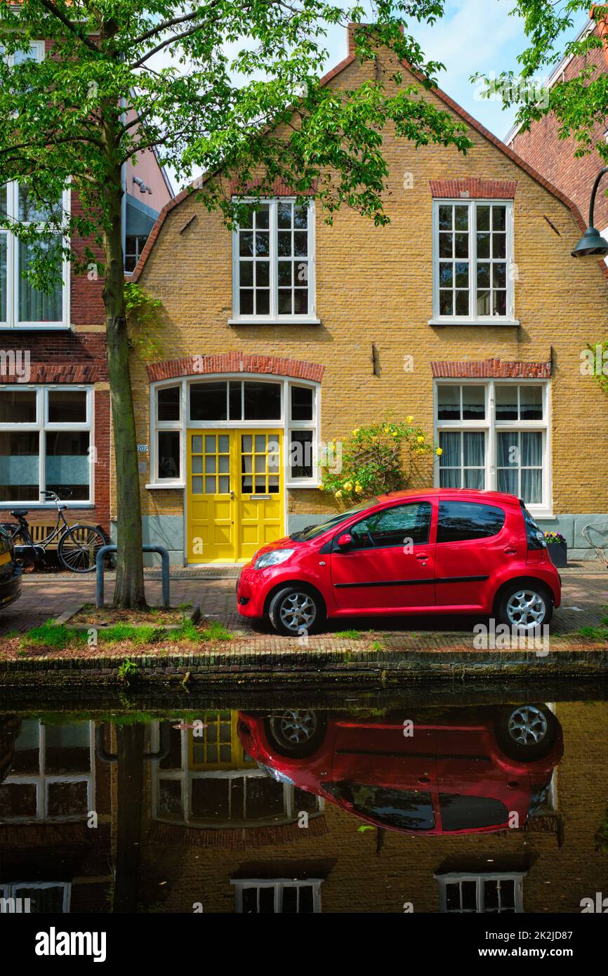 Red car on canal embankment in street of Delft. Delft, Netherlands ...