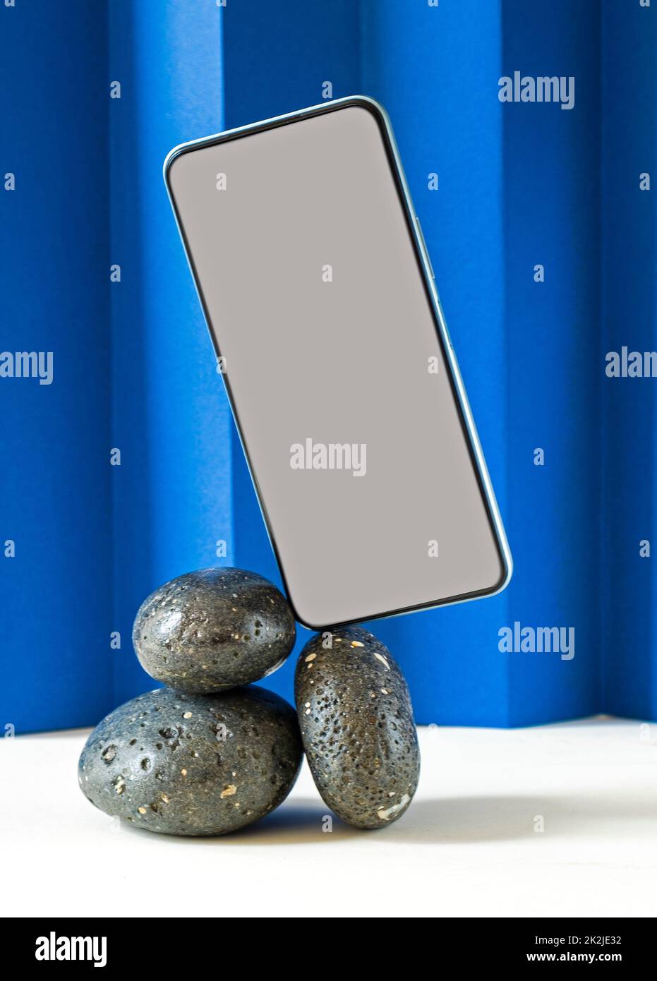 Composition of modern mobile phone with empty screen balancing on black ...