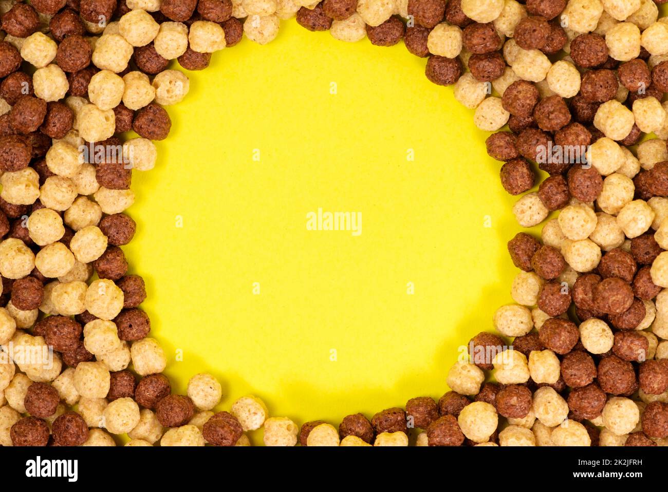 Breakfast cereal in the form of cocoa balls on a yellow background, a ...