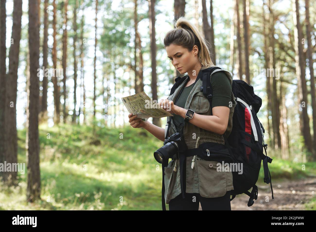Female hiker with big backpack using map for orienteering in the forest ...