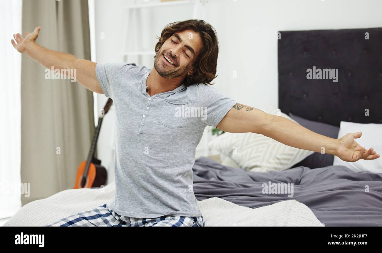 Mornings in are for slow starts and lazy days. Shot of young man waking up and stretching .in ...