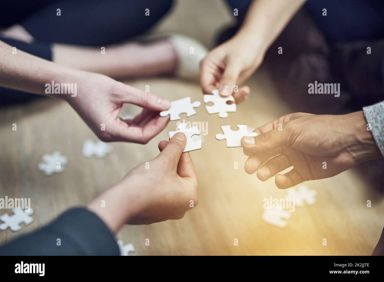 We fit together. Shot of a group of people building a puzzle together ...