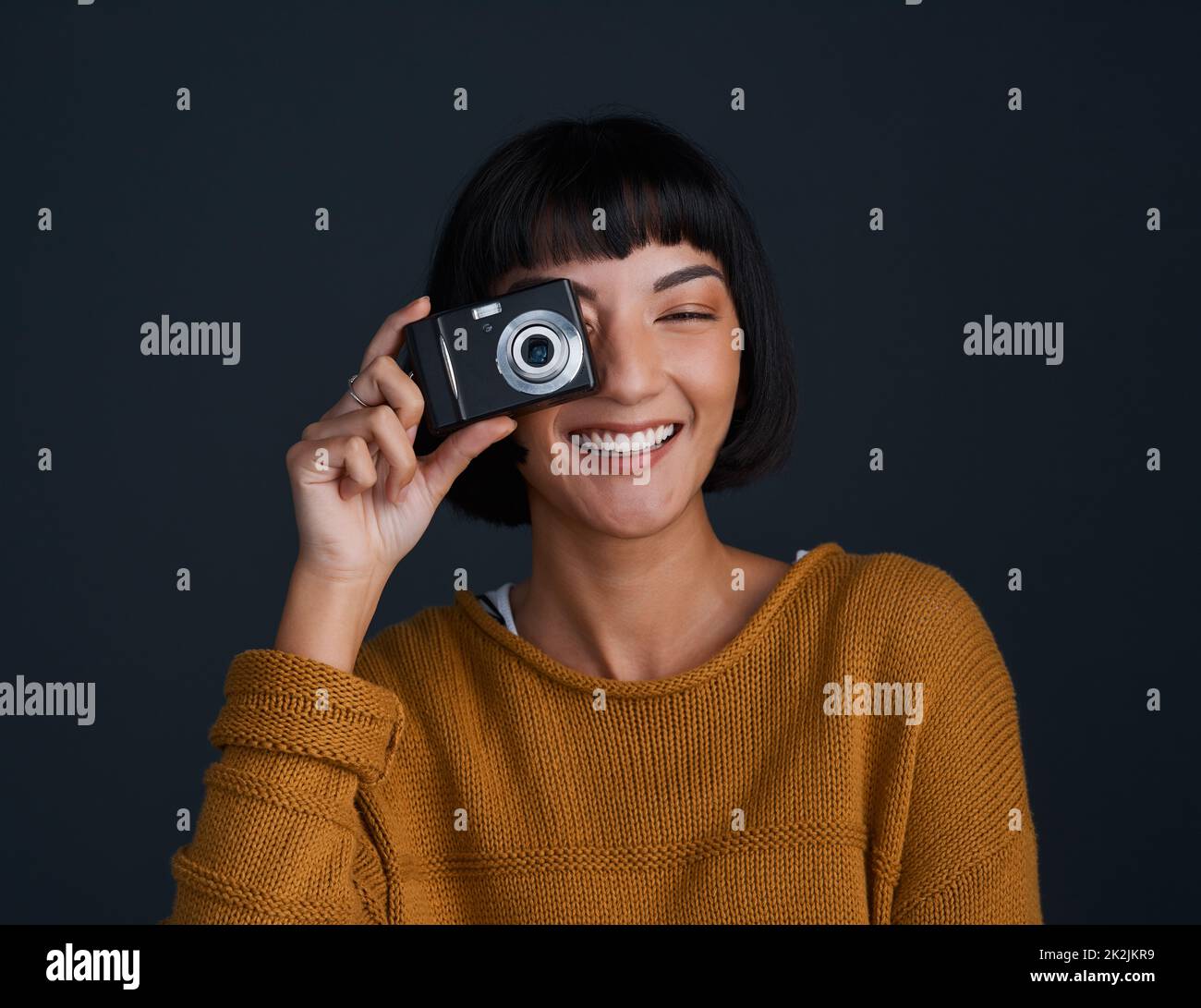 Smile, youre on camera. Studio portrait of a young woman using a camera ...