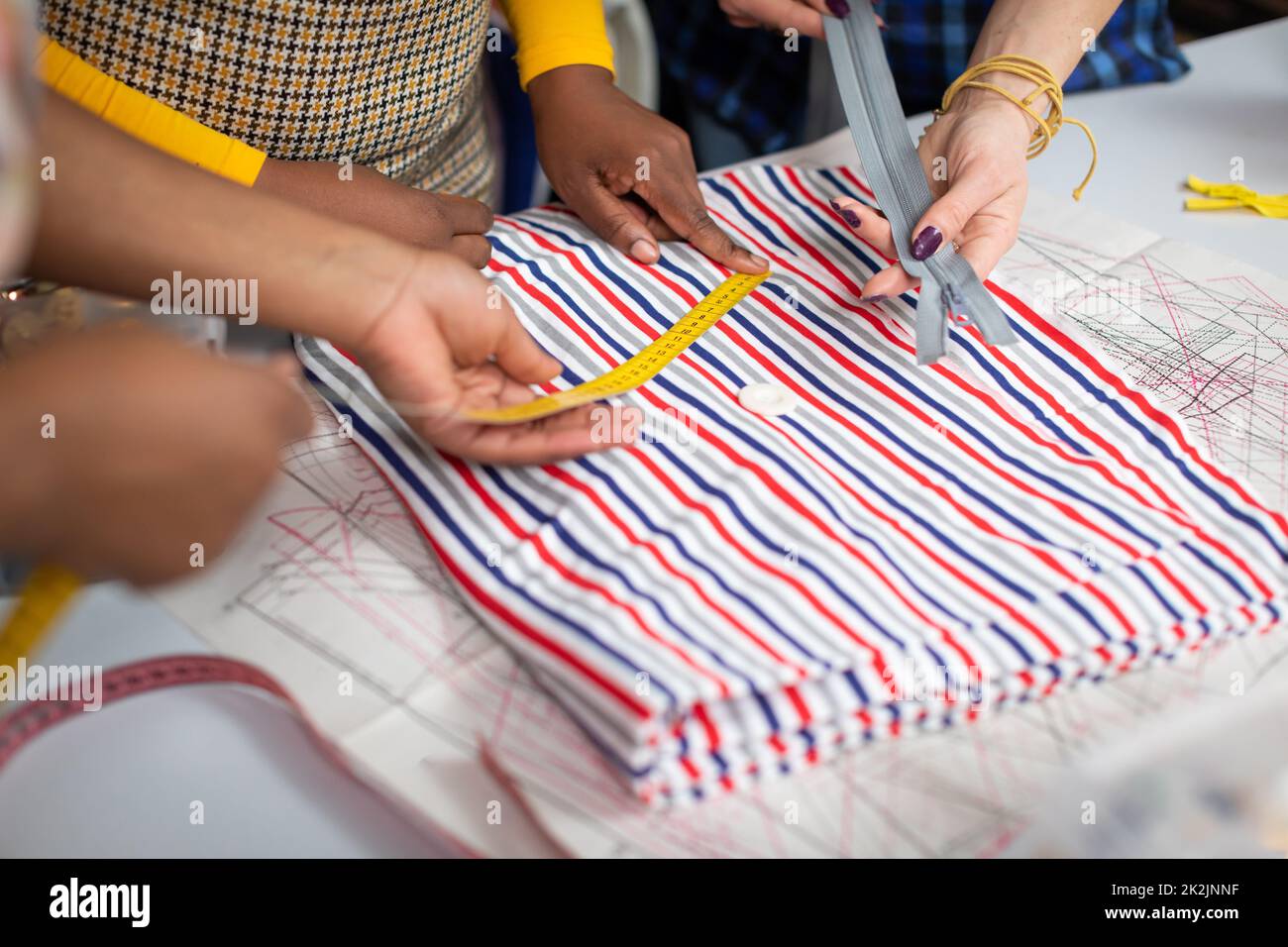 At the tailor's shop, the designer measures the fabric with a tailor's ...