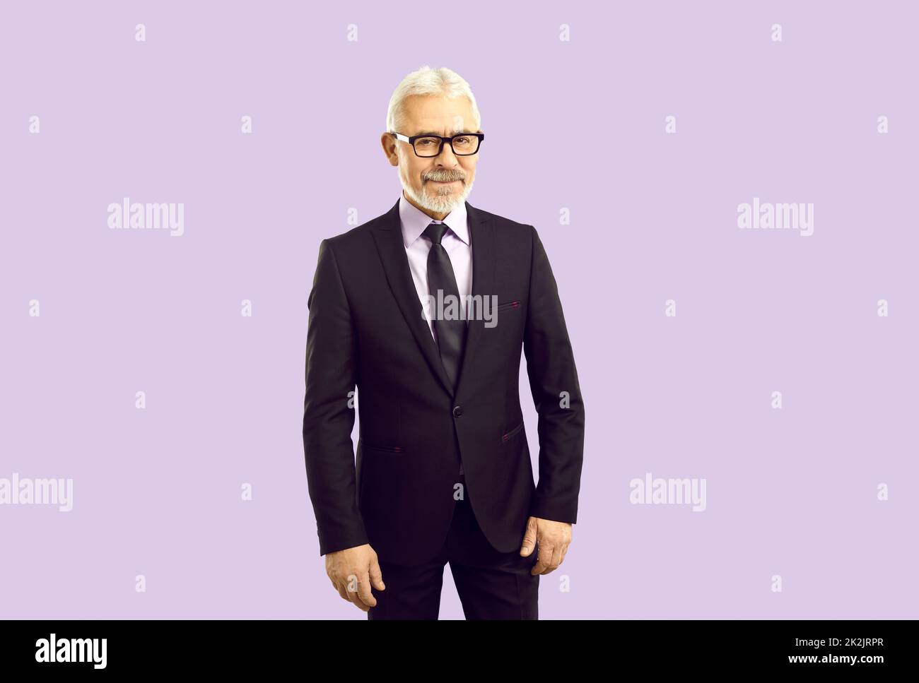 Senior man in formal suit posing at camera, smiling, isolated on purple ...