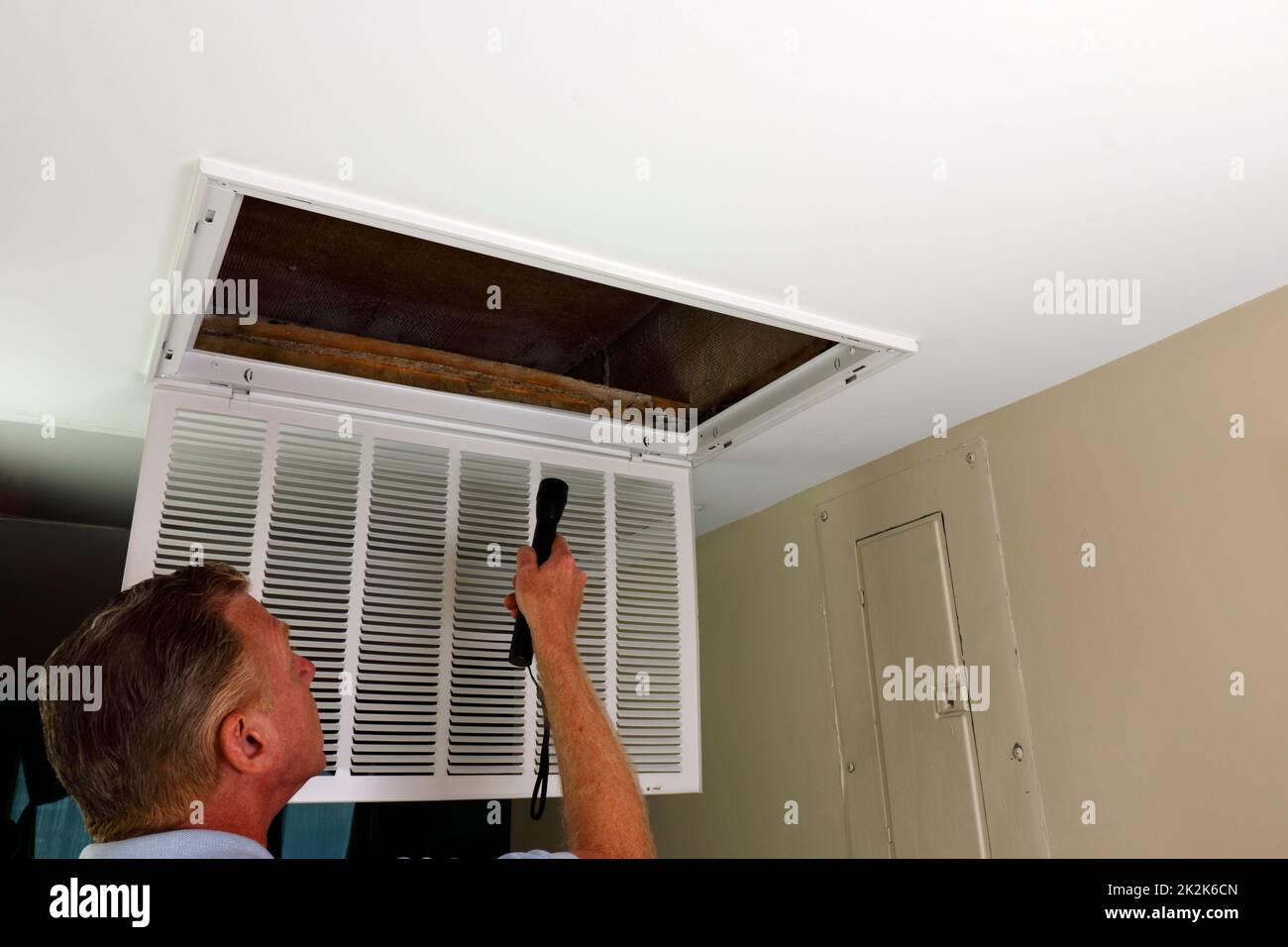 Adult Man Shining Flashlight Into HVAC Intake Vent in a Home Entry ...