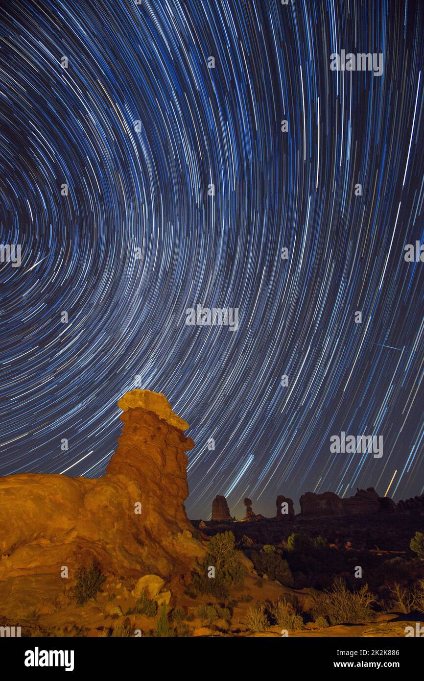 Star trails rotating around the North Star over a sandstone spire with ...