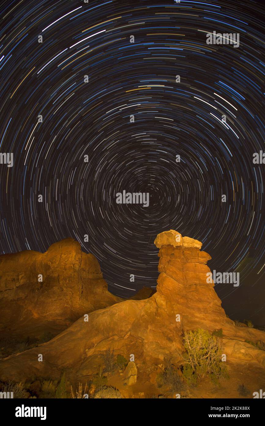 Star trails rotating around the North Star over a sandstone spire with ...