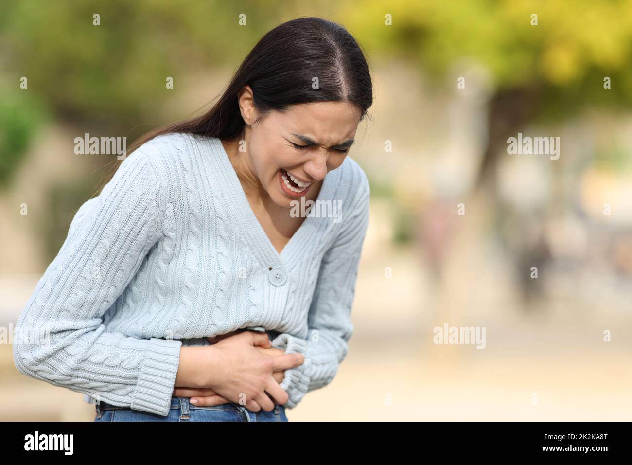 Woman suffering belly ache complaining in the street Stock Photo - Alamy