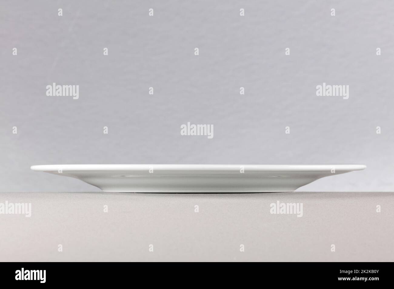 Side view of a white dinner plate on neutral background Stock Photo - Alamy