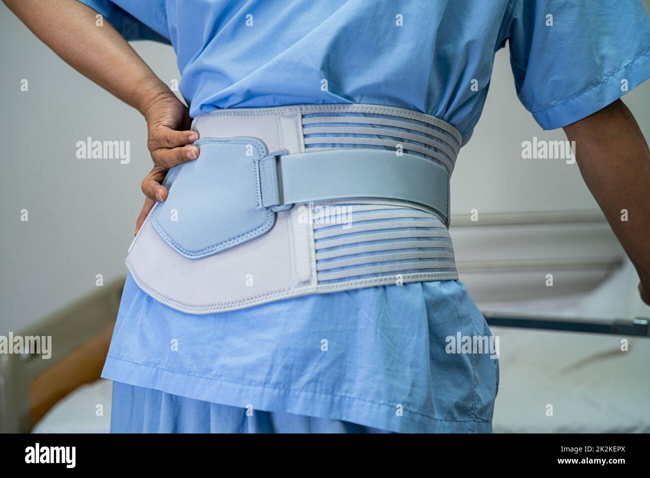 Asian lady patient wearing back pain support belt for orthopedic lumbar ...