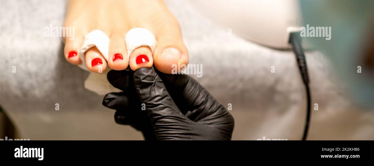 Nail painting process. A manicure master hand holds red painted ...