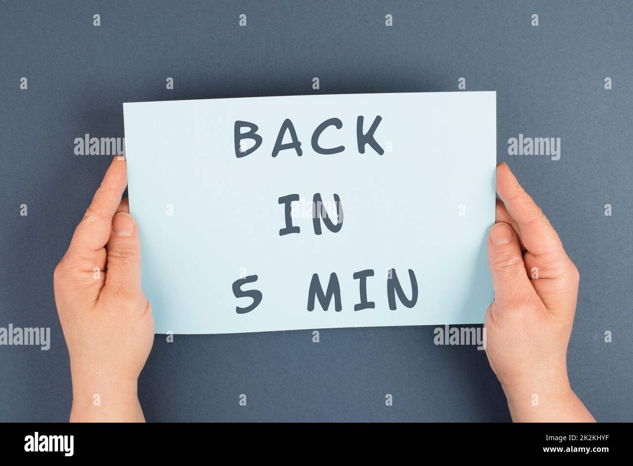 Back in 5 min ist standing on a paper, hands hold message, working ...