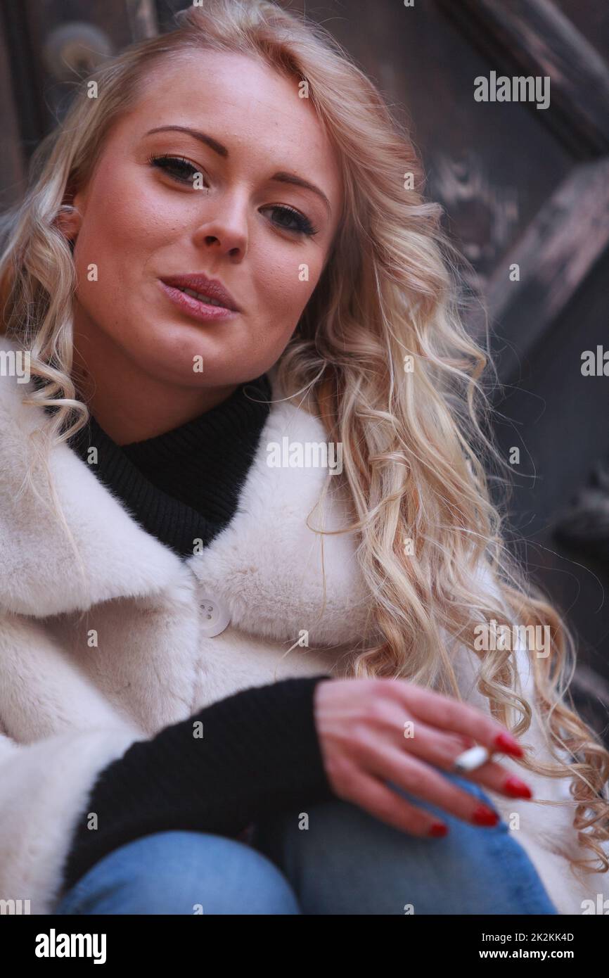 Smiling friendly young woman enjoying a cigarette outdoors Stock Photo ...