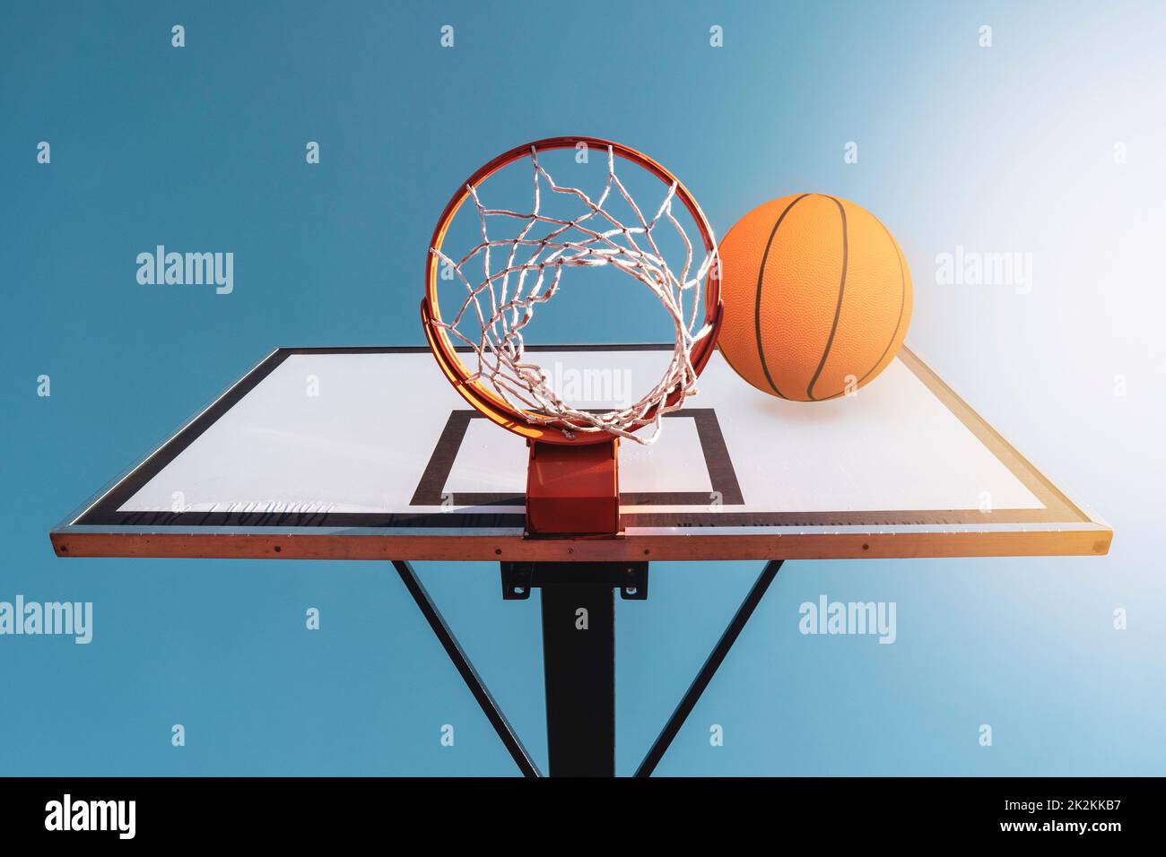 Orange basketball ball falling into the hoop Stock Photo - Alamy