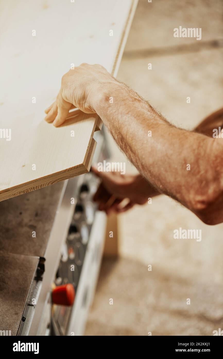 Carpenter lifting a sheet of wood to access controls below Stock Photo ...
