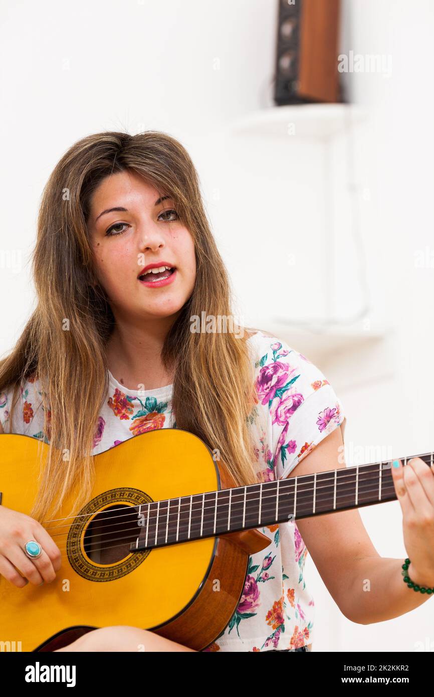 young woman or playing guitar and singing Stock Photo - Alamy