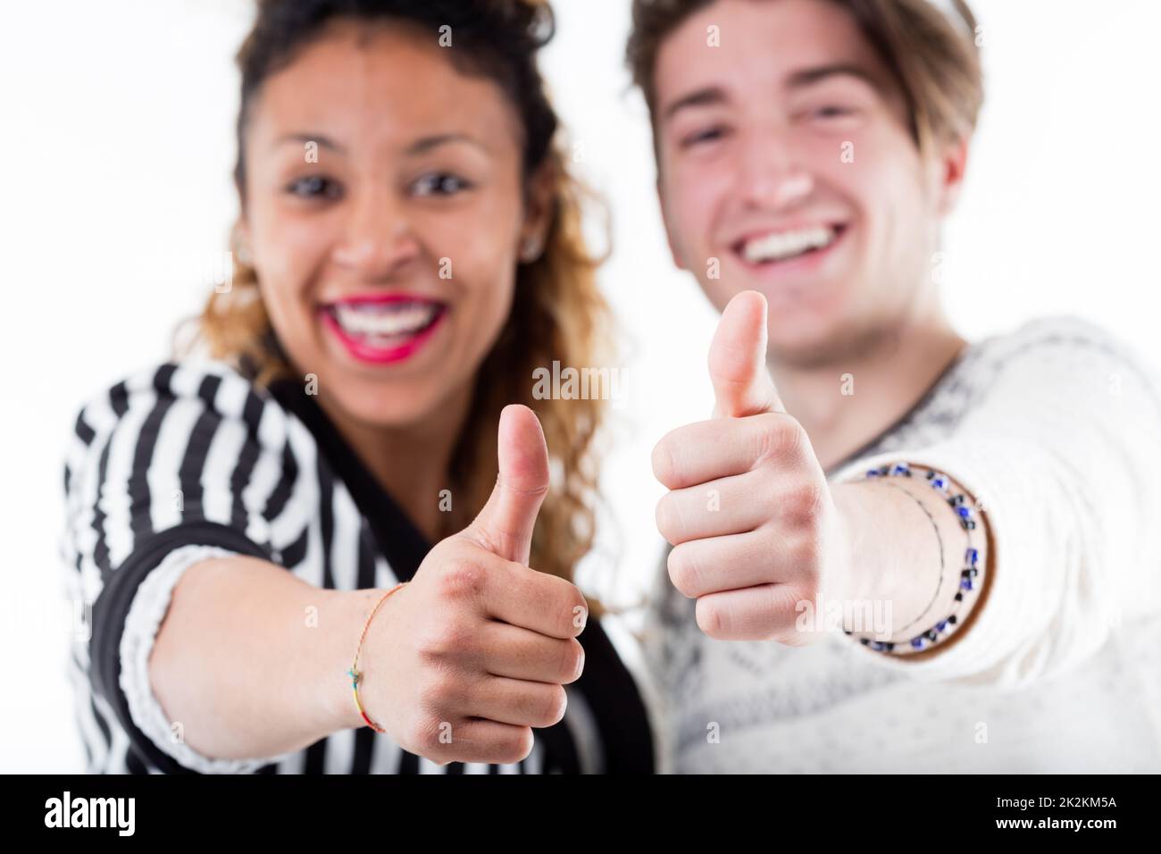 Two young cheerful people giving thumbs up Stock Photo - Alamy
