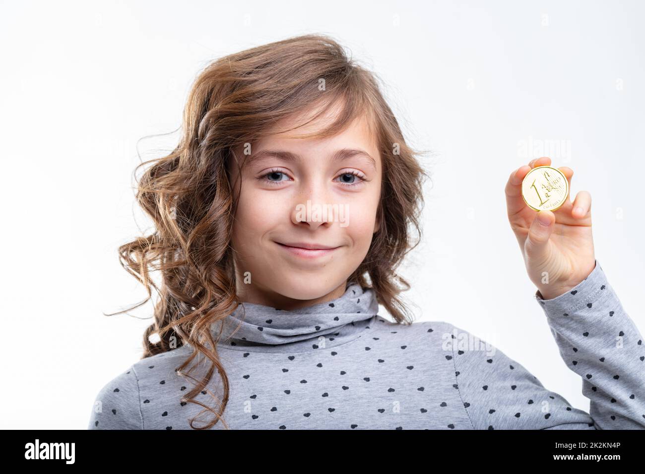 Little girl holding up a coin with a pleased happy smile Stock Photo ...