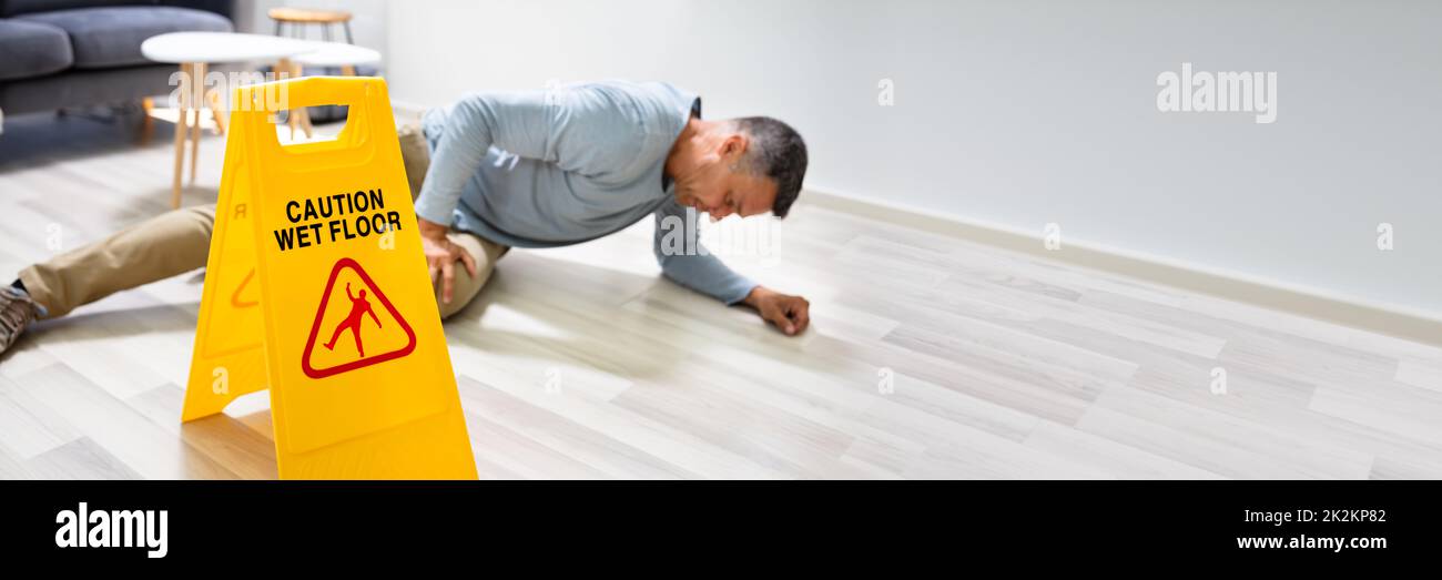 Man Falling On Wet Floor In Front Of Caution Sign Stock Photo - Alamy