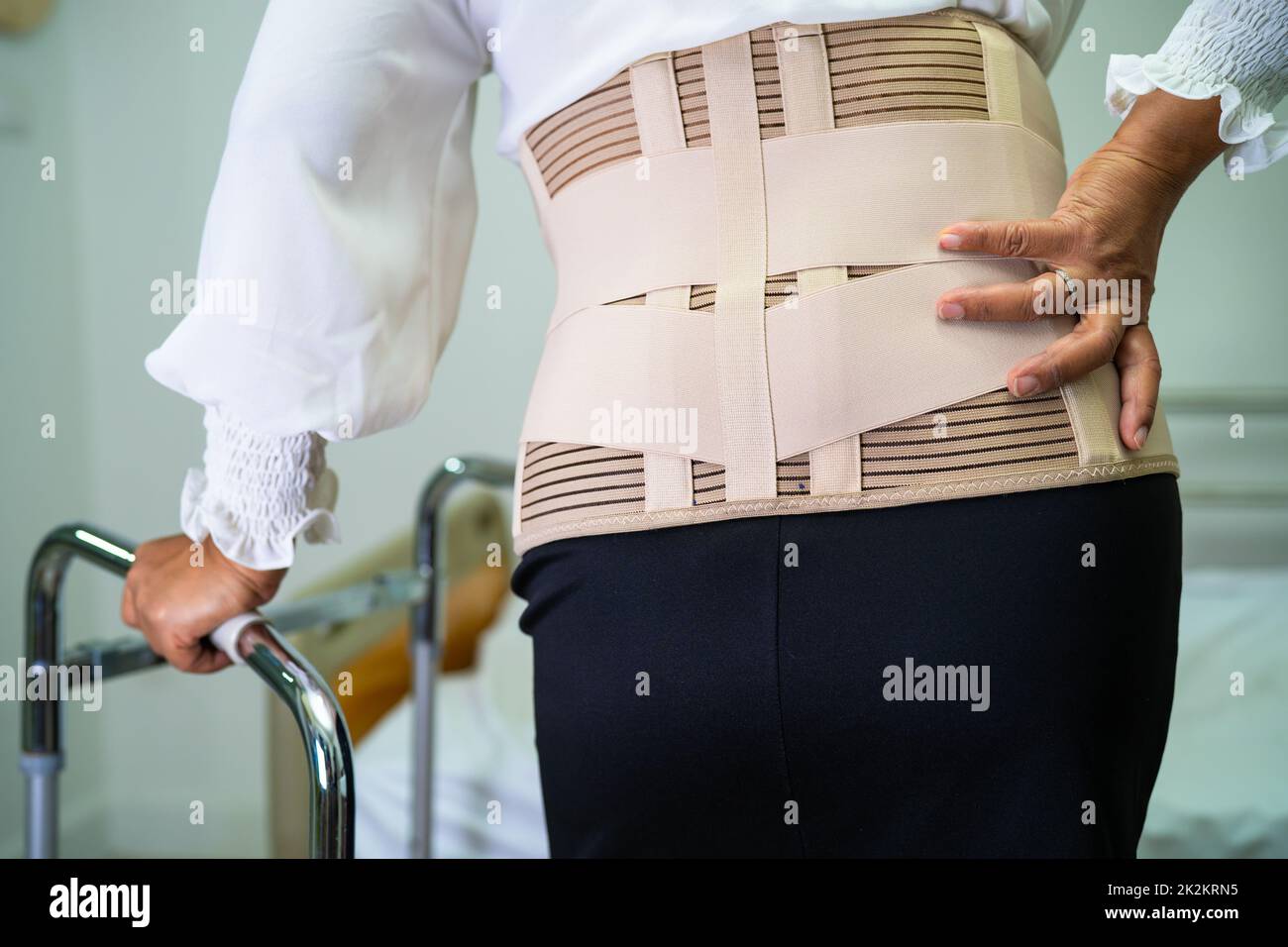 Asian lady patient wearing back pain support belt for orthopedic lumbar ...