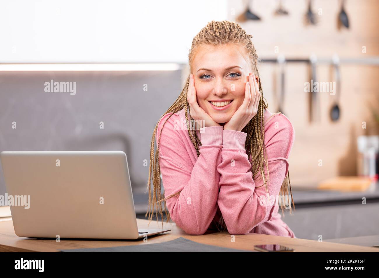 Young smiling woman sitting next to laptop Stock Photo - Alamy