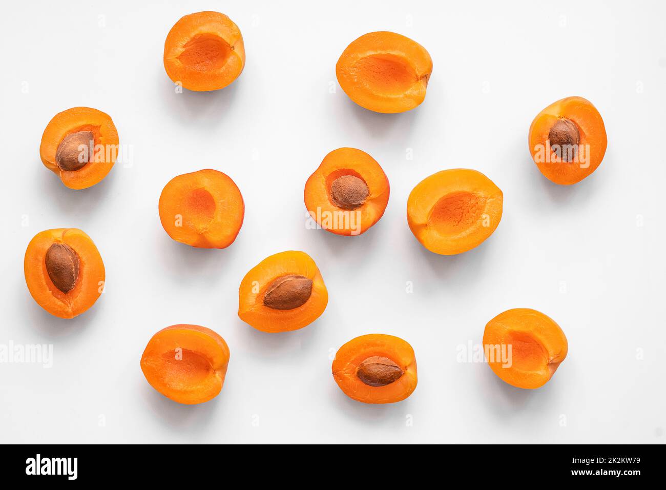 halves of pitted apricots lie on a light background in random order ...